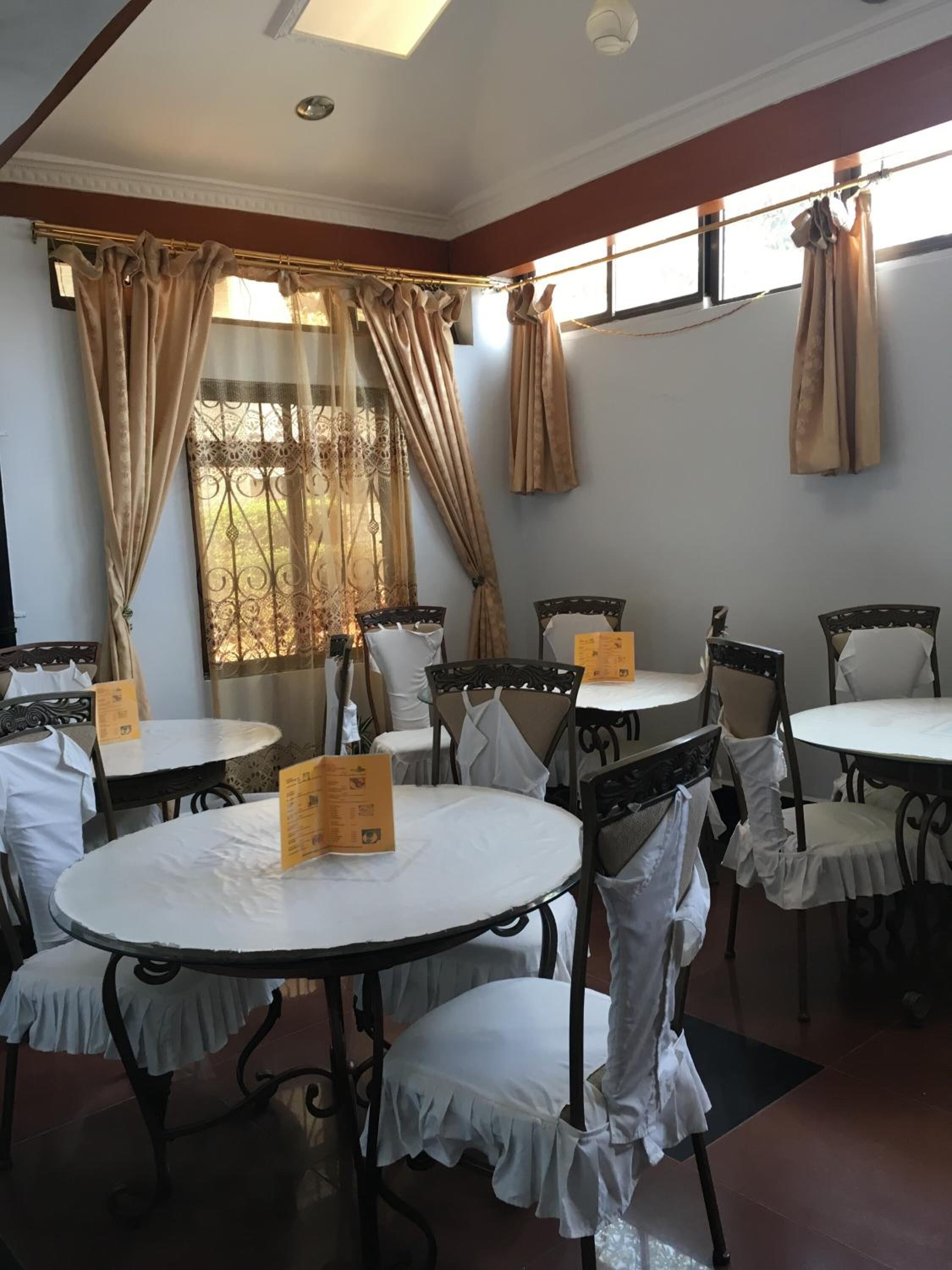 Uma área de refeições com mesas e cadeiras redondas, cada uma com um cardápio.