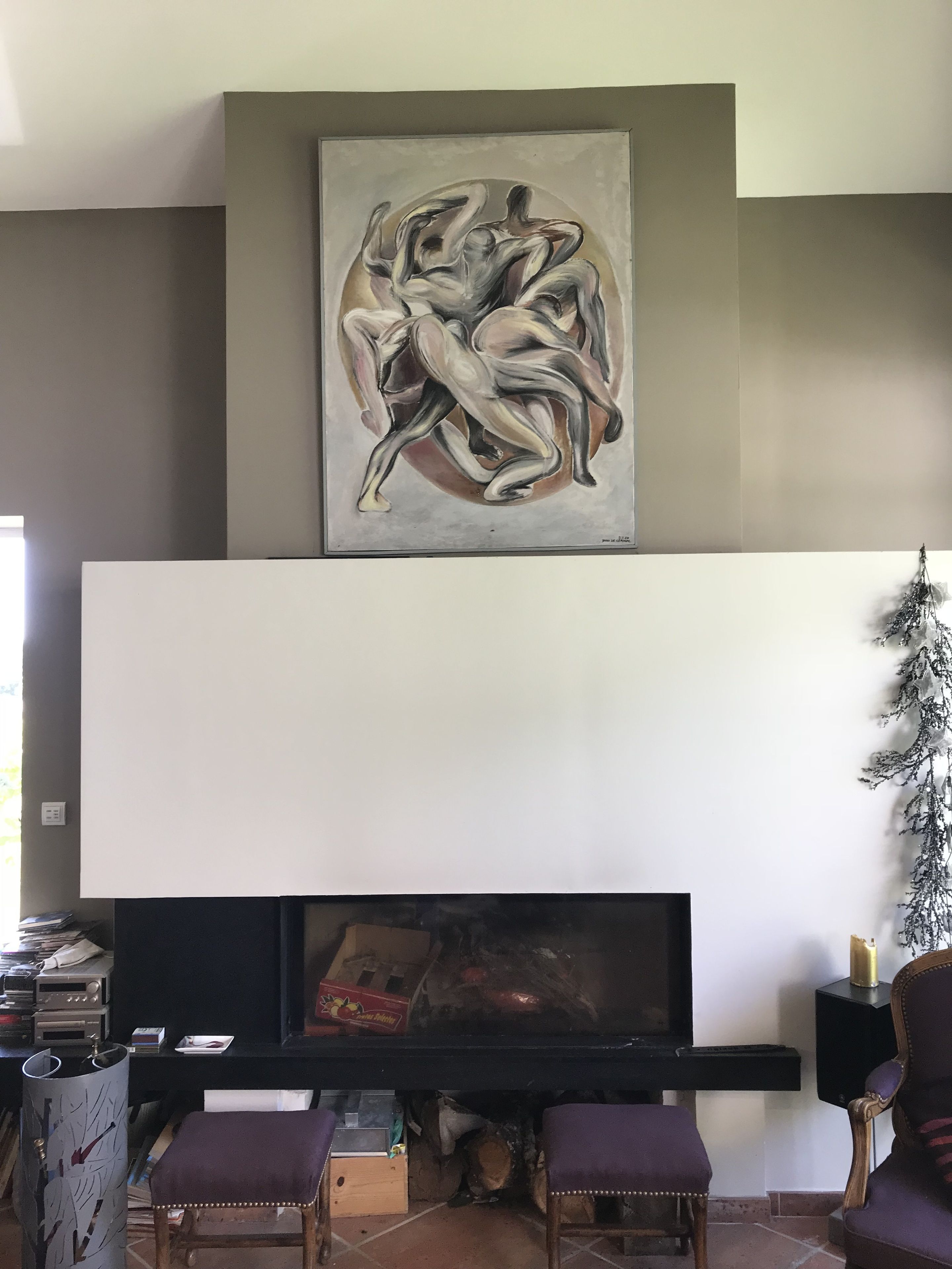 Uma sala de estar com lareira, um quadro abstrato pendurado na parede e uma televisão.