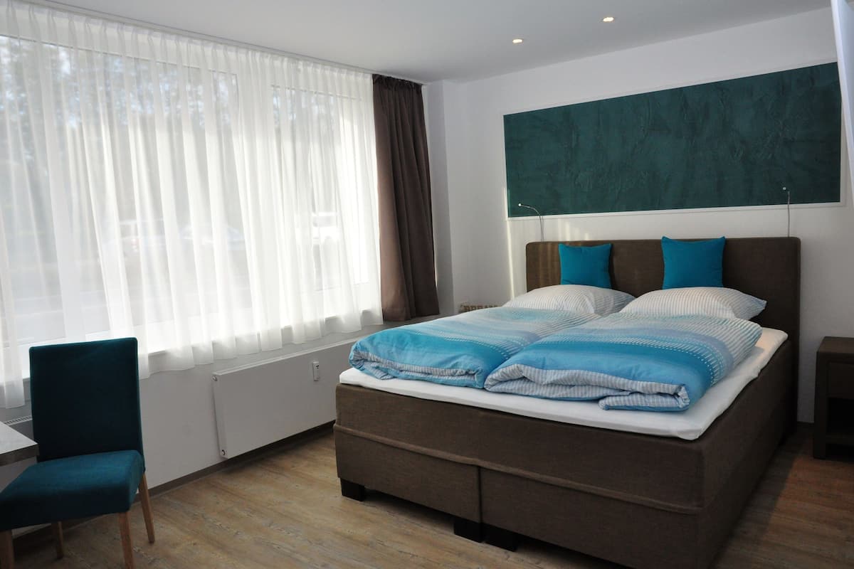 Quarto de hotel moderno com uma cama grande, uma escrivaninha e uma cadeira.
