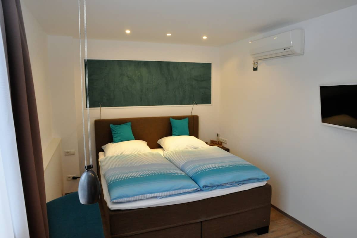 Quarto com cama, ar condicionado na parede e televisão.