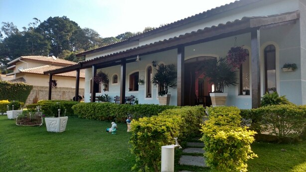 Um edifício com alpendre coberto, gramado bem cuidada e plantas em vasos.