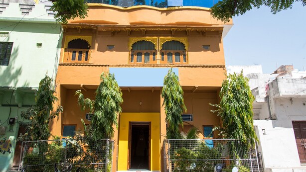 Um edifício de dois andares com fachada amarela, janelas em arco e uma varanda.