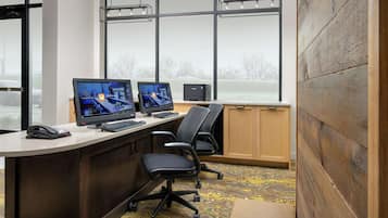 Um escritório moderno com dois monitores, um telefone de mesa e duas cadeiras de escritório.