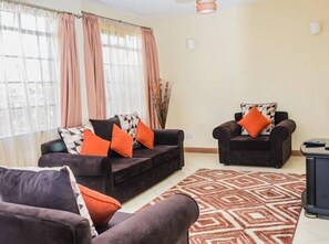 Uma sala de estar com um sofá, duas poltronas e um tapete estampado.