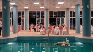 Um espaço interno com piscina, assentos dispostos ao redor, e grandes janelas.