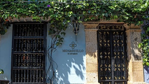 Fachada de um edifício com uma placa indicando 'MONAGUILLO DE GETSEMANI', um portão de ferro forjado e uma parede coberta de hera.