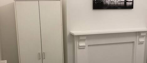 Quarto com guarda-roupa branco, lareira e quadro na parede de uma roda gigante.