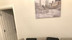 Um sofá modular cinza com almofadas pretas e cinzas, uma porta e uma pintura de uma paisagem nevada na parede.