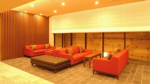 Um lounge moderno com sofás laranja, um banquinho marrom e uma parede de madeira.