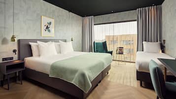 Quarto de hotel moderno com uma cama grande, uma cama menor, uma escrivaninha e uma cadeira.