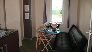 Uma cozinha compacta com mesa e cadeiras, um sofá preto e uma janela com cortinas.