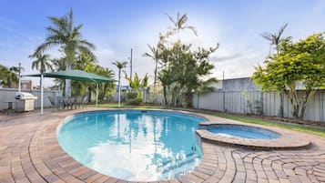 Um quintal com piscina, móveis de varanda e churrasqueira.
