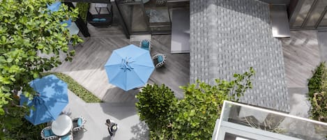 Vista aérea de uma área moderna ao ar livre, com terraço, assentos e guarda-sóis.