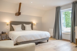 Quarto moderno com cama grande, abajures, parede de destaque em madeira e vista pela janela com cortinas.