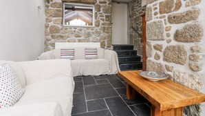 Um quarto acolhedor com parede de pedra, um banco de madeira e uma cama com almofadas listradas.