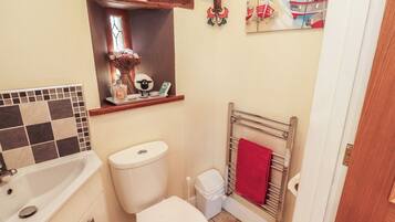 Casa de banho com sanita, lavatório e suporte para toalhas.