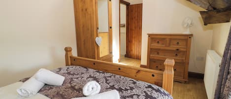 Um quarto com cama de madeira, cômoda, espelho e ventilador de teto.