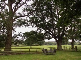 Uma área gramada com cerca de madeira e uma mesa com cadeiras.