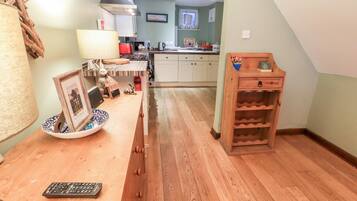 Cozinha com piso de madeira, armário de madeira, espaço para vinhos e um controle remoto sobre o balcão.