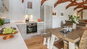 Uma cozinha moderna com teto de madeira, forno embutido e área de refeições com mesa e cadeiras de madeira.