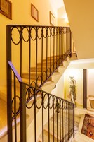 Uma escadaria com grades de metal ornamentadas e um tapete estampado na base.
