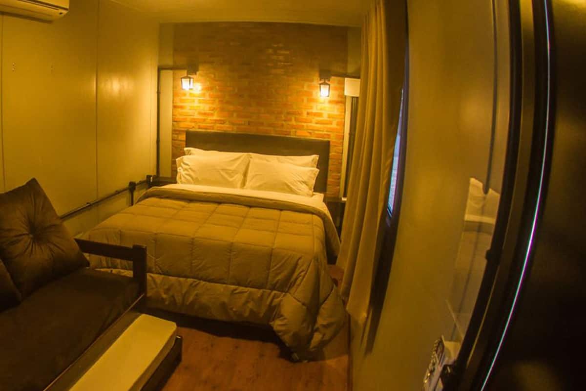 Quarto compacto com cama, uma mesinha e um sofá.