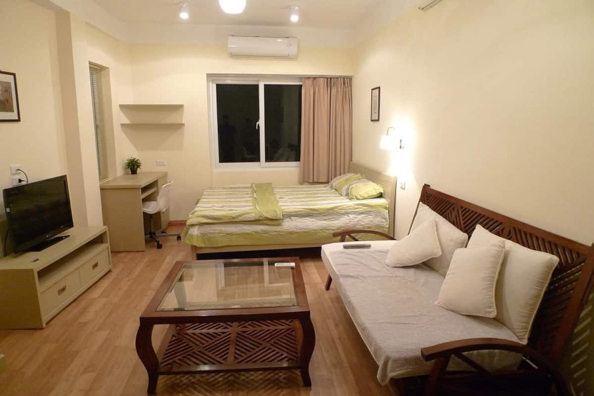 Quarto de hotel pequeno com uma cama, um sofá, uma televisão, uma secretária e uma janela.