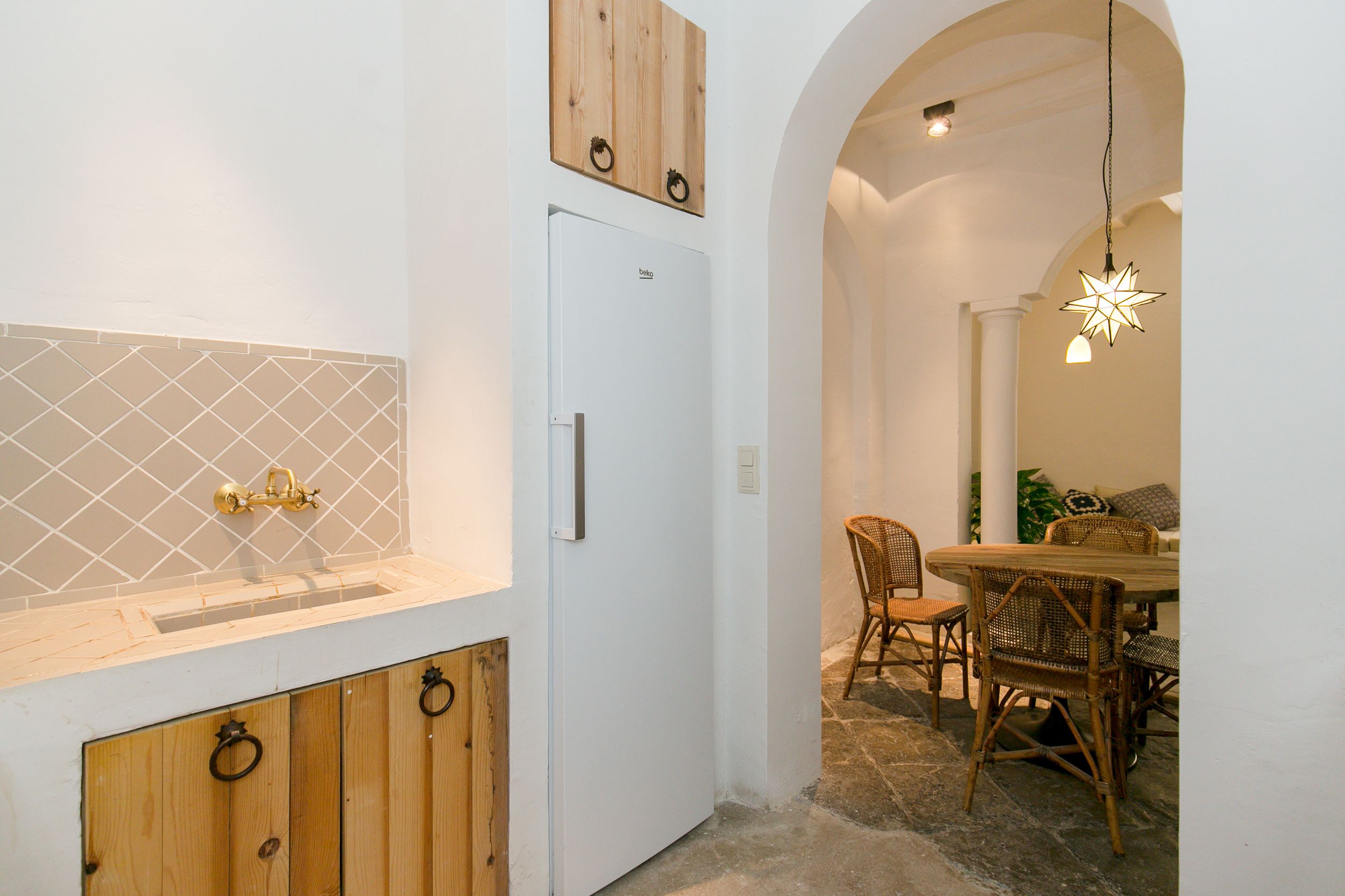 Cozinha com geladeira branca, armários de madeira e painel de azulejos.