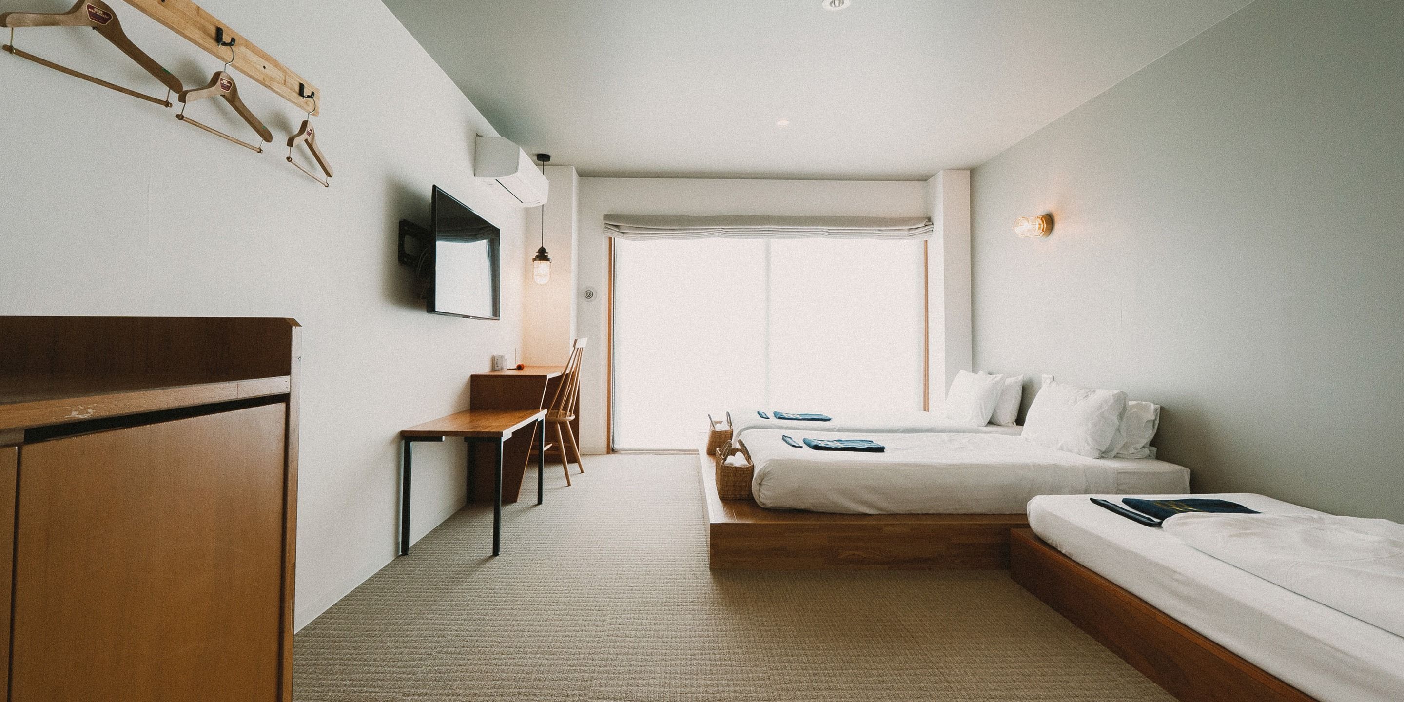 Quarto de hotel com cama, secretária e cadeira.
