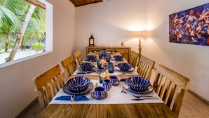 Uma área de refeições com uma mesa de madeira posta para seis pessoas, cercada por cadeiras de madeira.