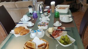 Uma mesa de café da manhã com croissants, pão, queijo, presunto e uvas.