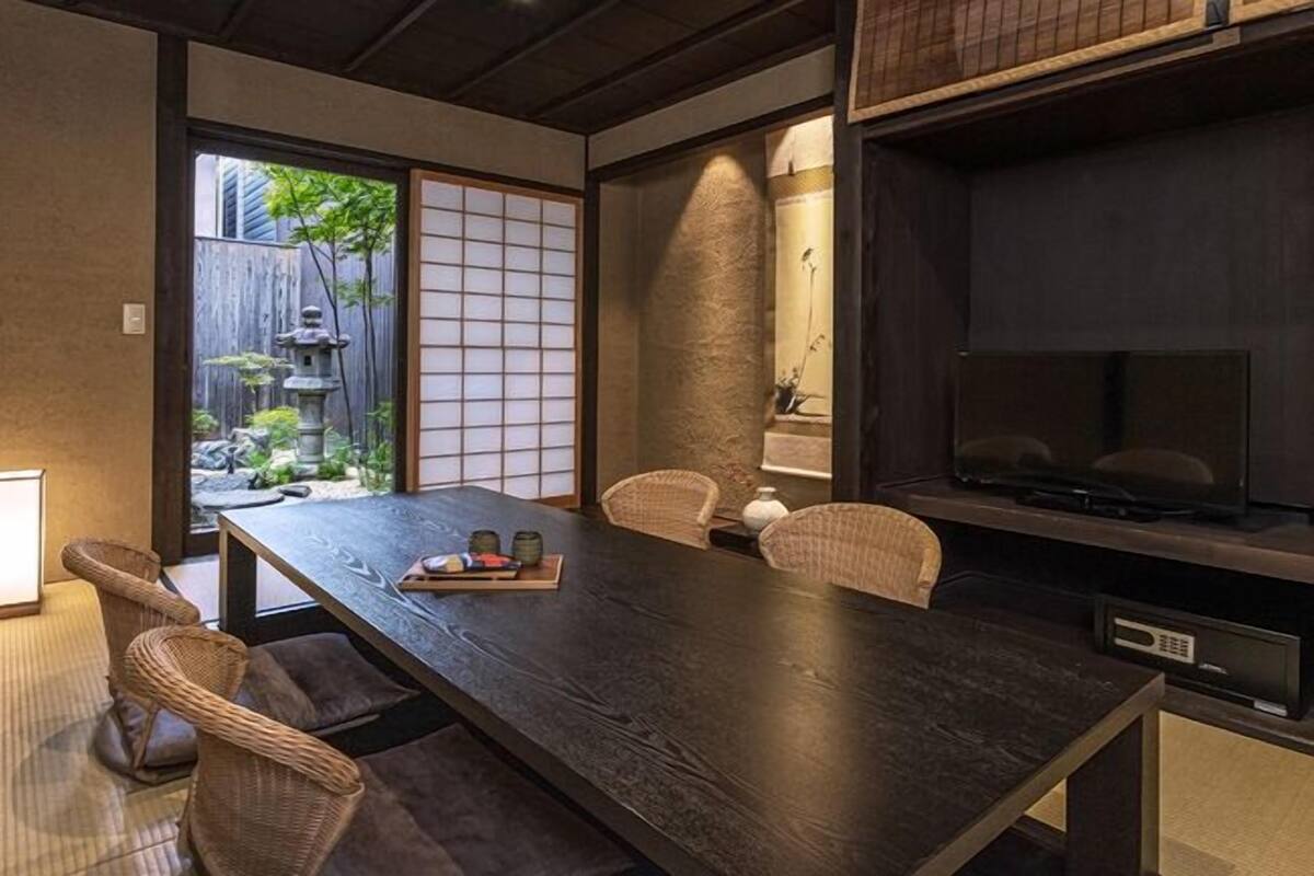 Quarto tradicional em estilo japonês, com tatames, uma mesa baixa e uma televisão.