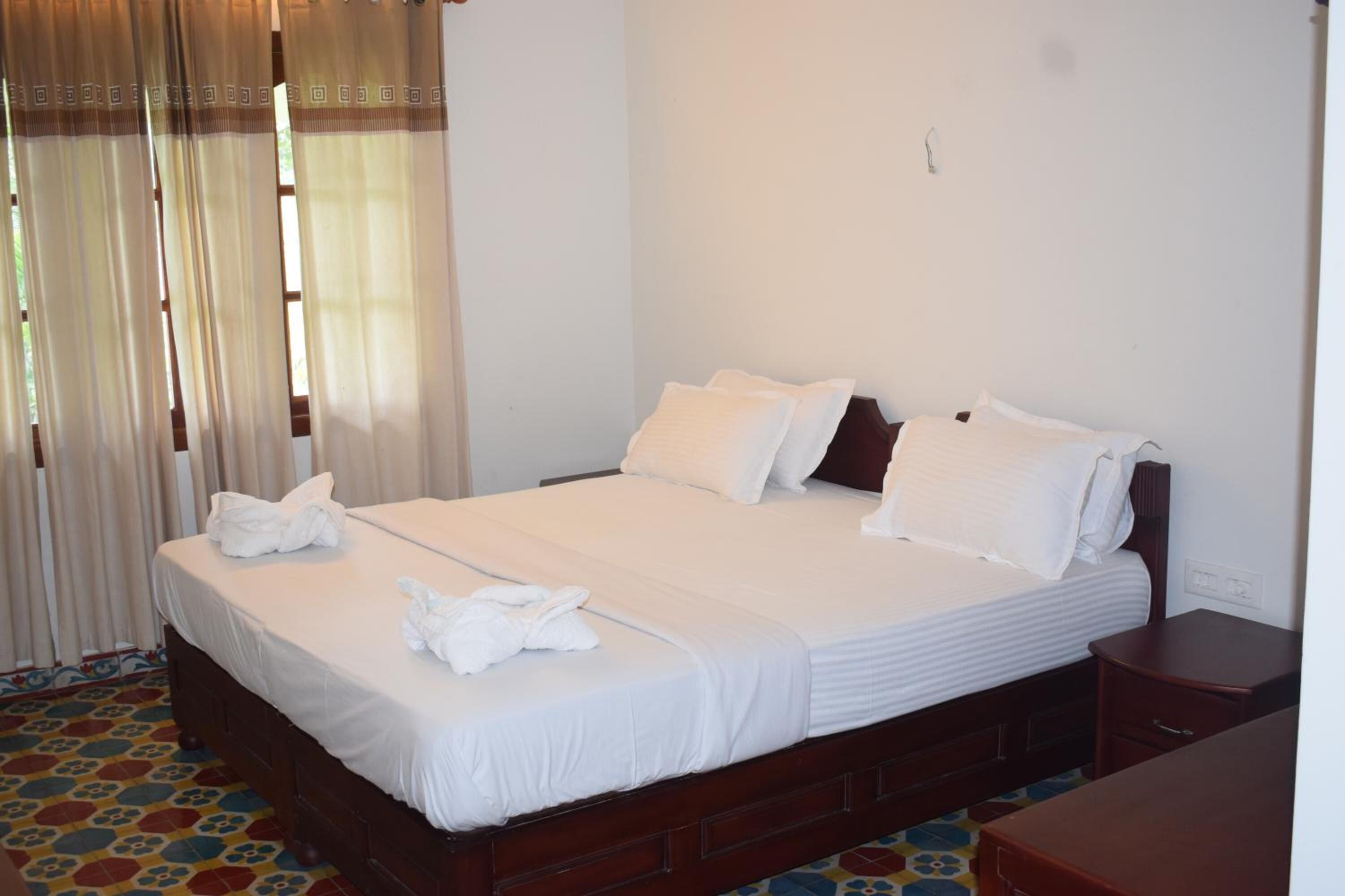 Cama bem arrumada com lençóis e toalhas brancas, cabeceira de madeira e mesa de cabeceira.