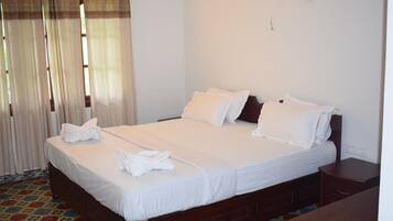 Cama bem arrumada com lençóis e toalhas brancas, cabeceira de madeira e mesa de cabeceira.
