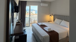 Quarto de hotel com cama, televisão, escrivaninha, cadeira, varanda e vista para edifícios.