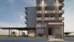 Um hotel moderno com entrada coberta, várias varandas e vista clara da paisagem circundante.