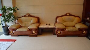Quarto com duas poltronas de couro, uma mesinha, um vaso de planta e um tapete vermelho.