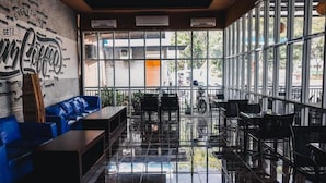 Um café moderno com um sofá azul, cadeiras pretas e piso de azulejos.