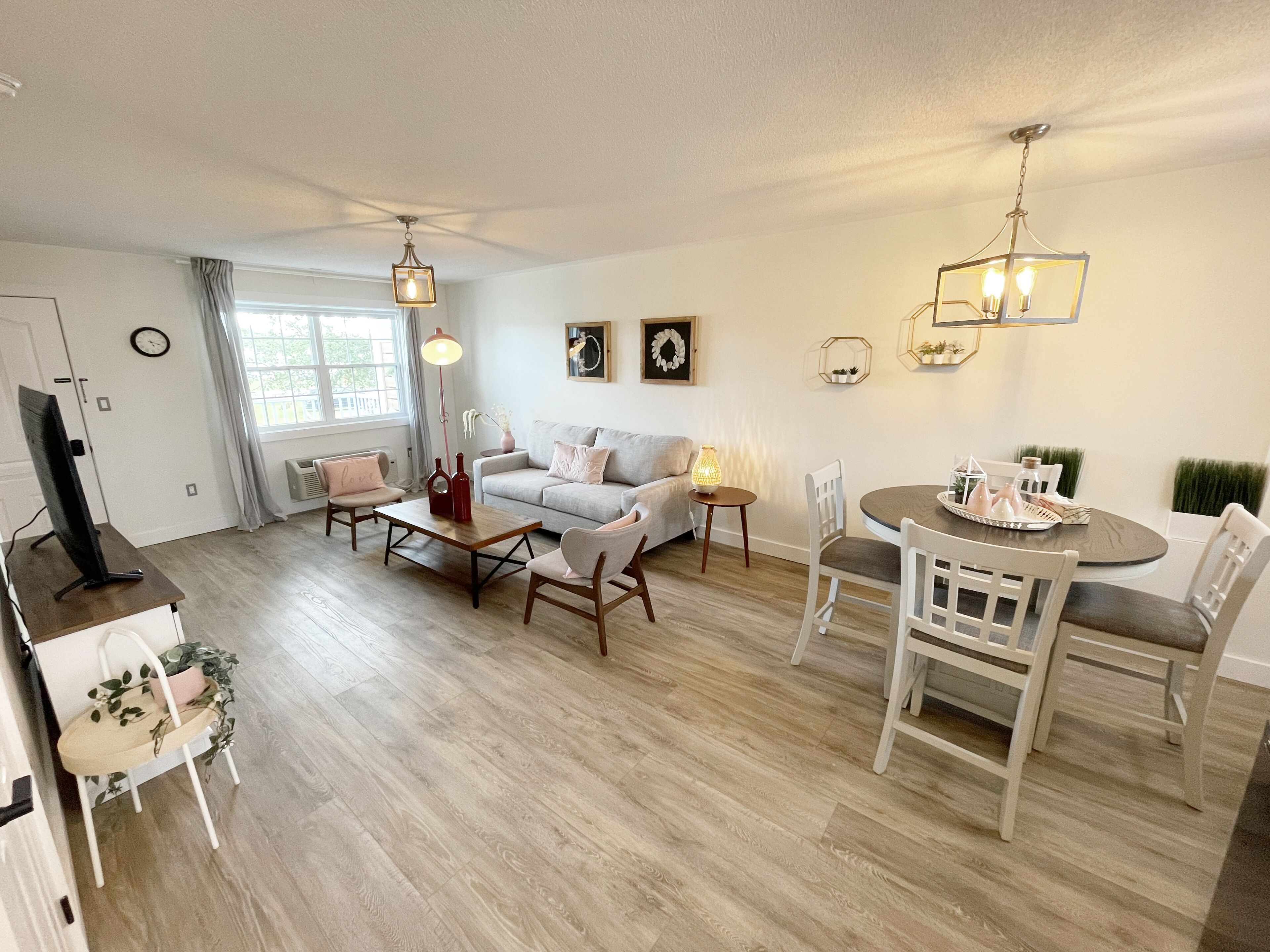 Uma sala de estar ampla com sofá, cadeiras, mesa de jantar e televisão.
