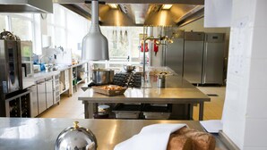 Cozinha moderna com eletrodomésticos de aço inoxidável, uma ilha grande e panelas penduradas.