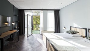 Quarto moderno com cama, escrivaninha, cadeira e televisão.