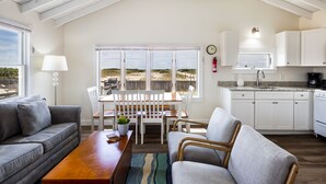 Uma sala de estar ampla com teto alto, um espaço de jantar com vista e uma cozinha com armários brancos.