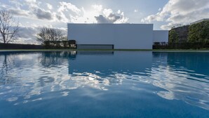Piscina com um edifício moderno ao fundo.