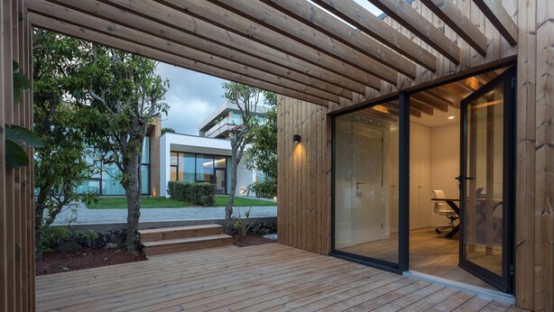 Um deck de madeira com uma porta de vidro que dá para um interior moderno.