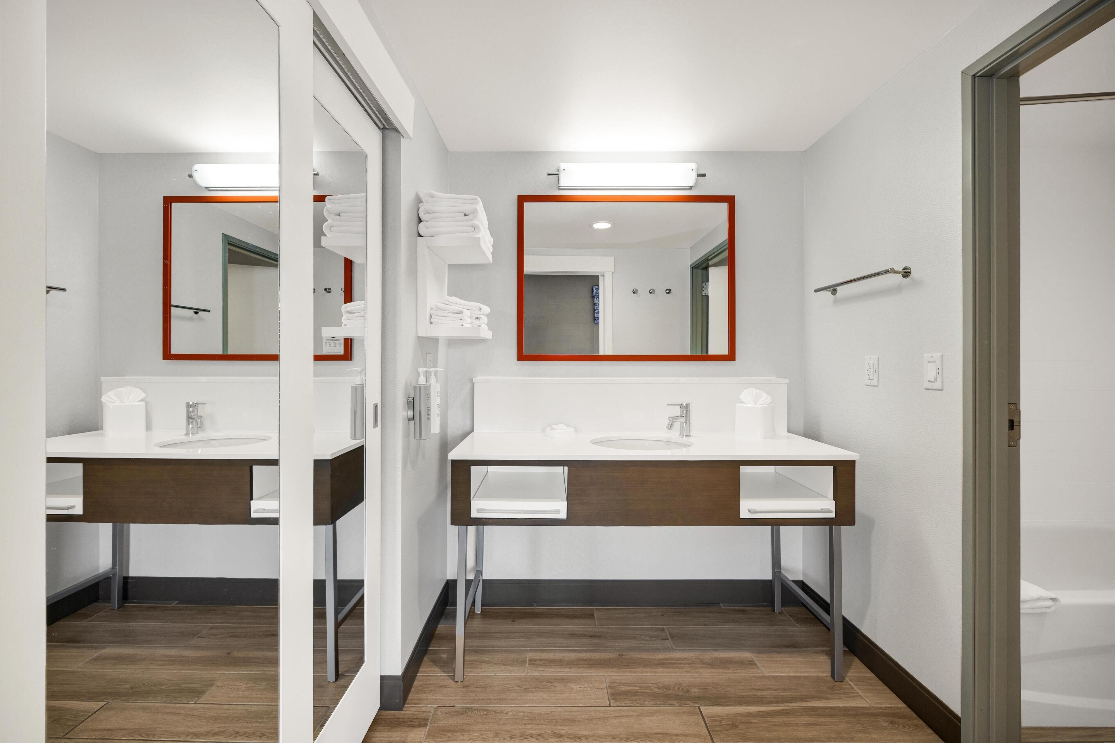 Casa de banho moderna com duas pias, um espelho grande e um porta-toalhas.