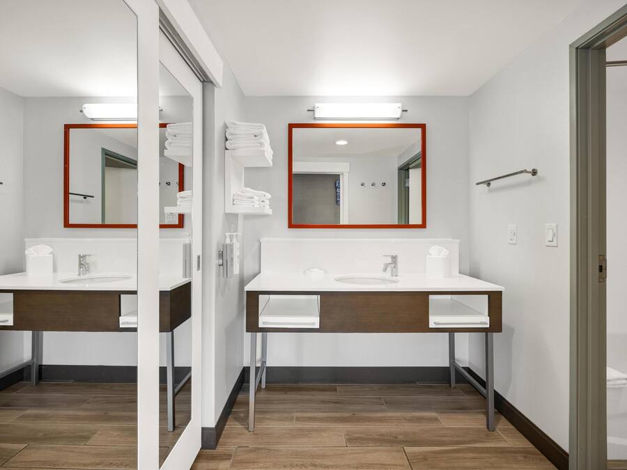 Casa de banho moderna com duas pias, um espelho grande e um porta-toalhas.