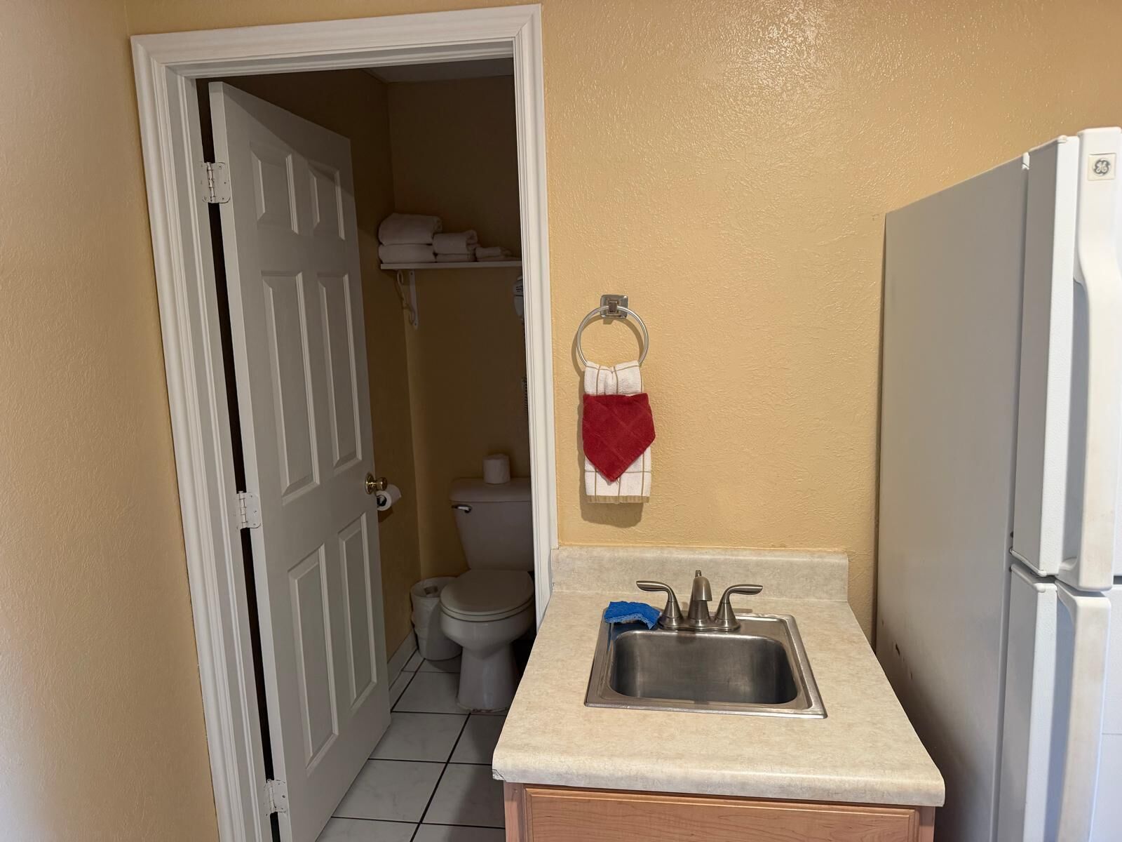 Uma casa de banho compacta com lavatório, sanita e um porta-toalhas com uma toalha vermelha.