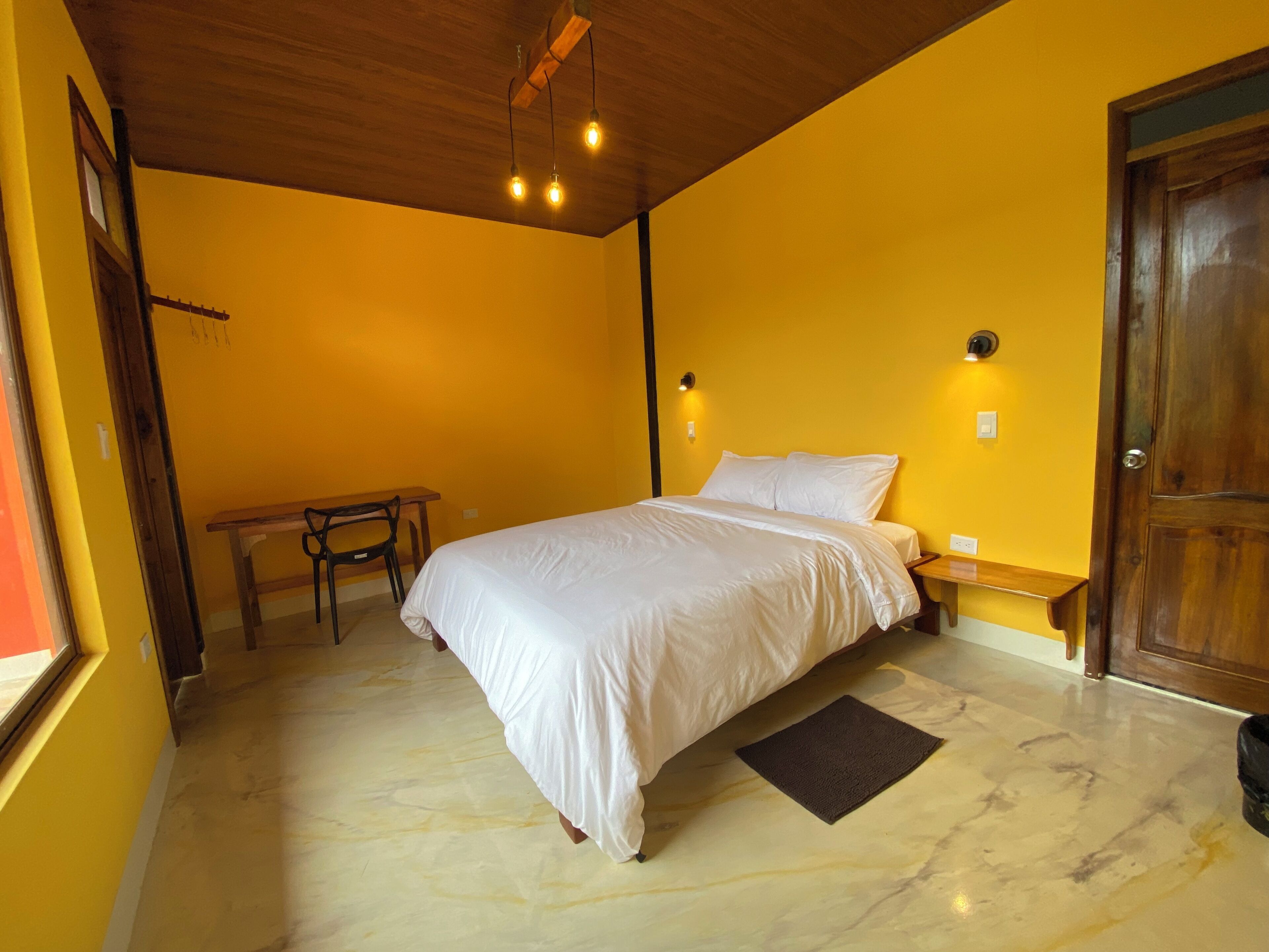 Um quarto com uma cama, uma escrivaninha e uma cadeira.