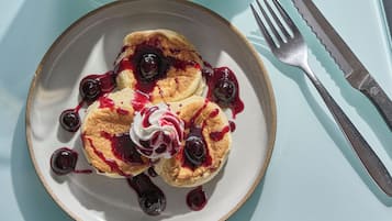 Um prato de panquecas com mirtilos e chantilly sobre uma mesa.
