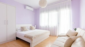Quarto com cama, sofá, guarda-roupa e janela com cortinas.